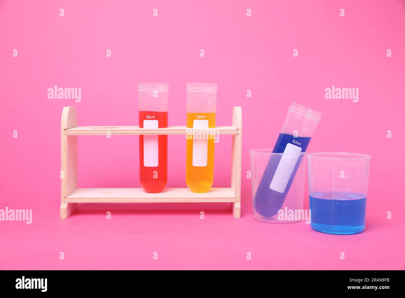 Beakers and test tubes with colorful liquids in wooden stand on bright ...