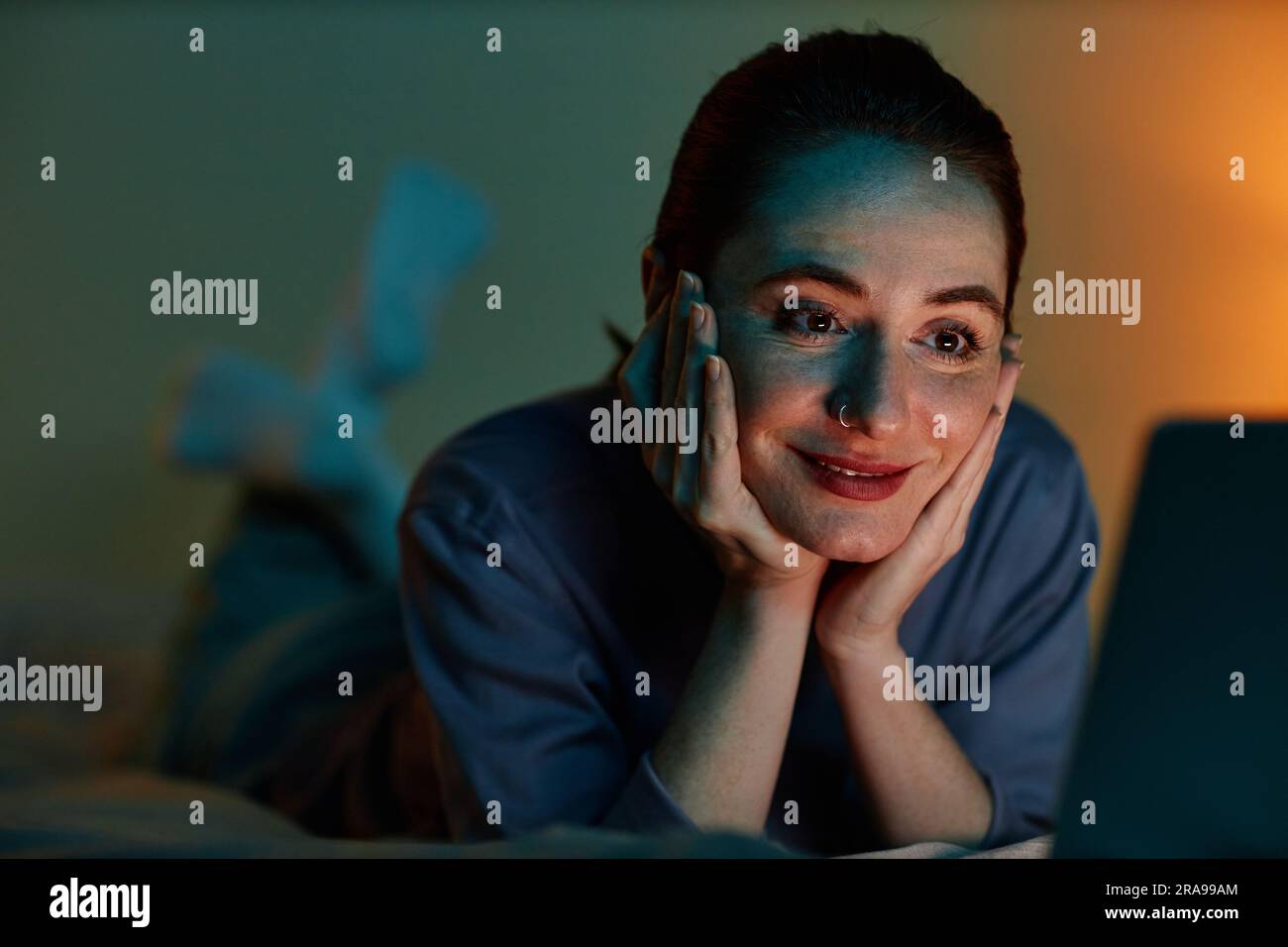 Closeup portrait of young woman binge watching movies at night while ...