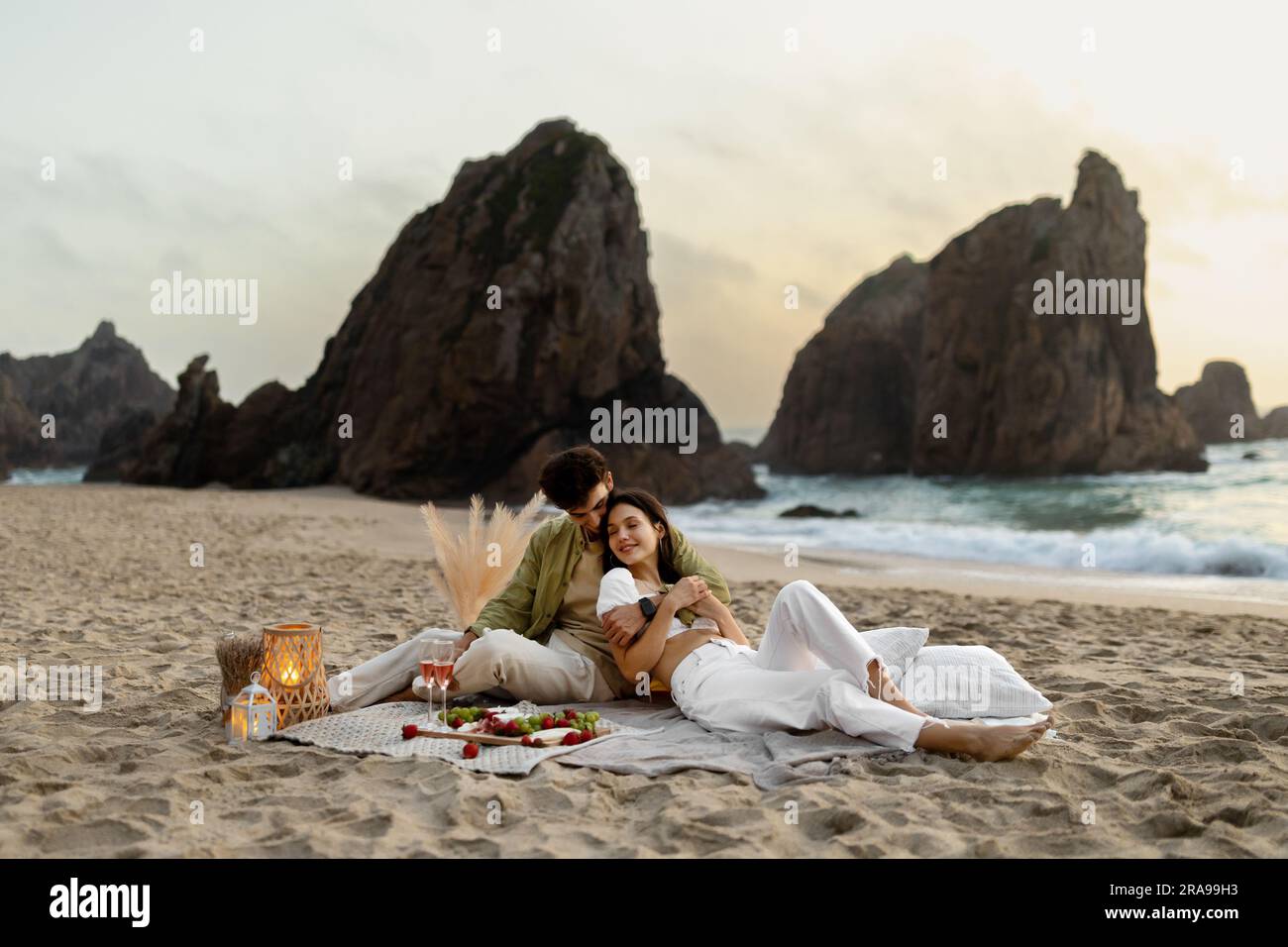 Young couple having romantic picnic at the beach, embracing and lying ...