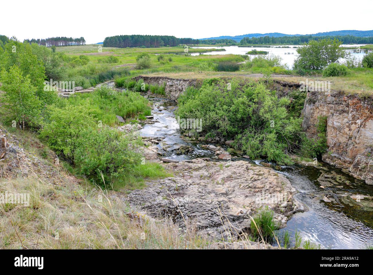 Limestone cliffs above a calm overgrown river. Summer landscape Stock ...