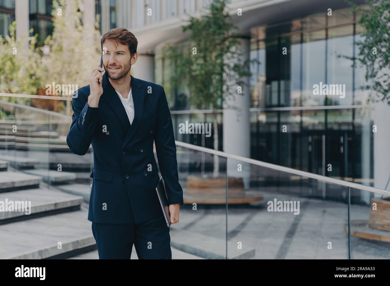 Fashionable businessman uses tech, has phone call, holds gadget, poses ...