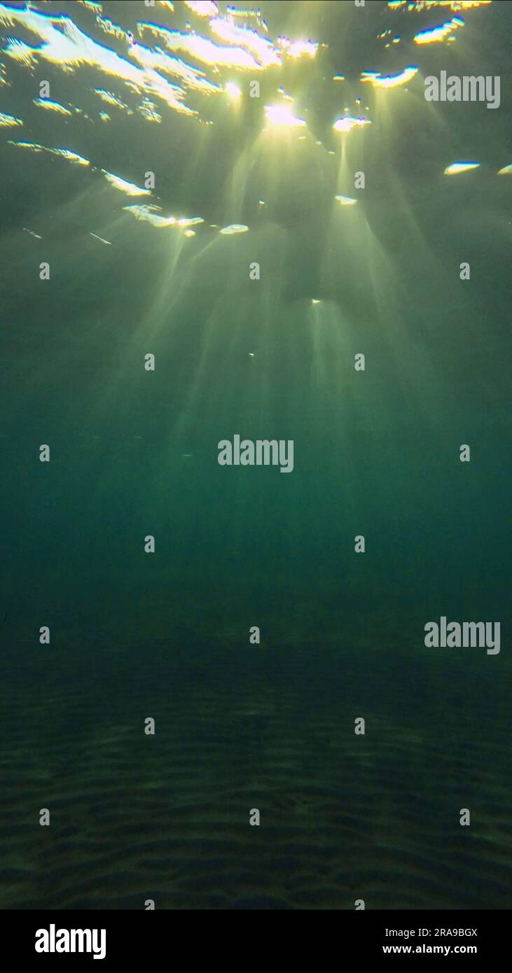 Low angle wide shot sun rays penetrating surface of water in the ...