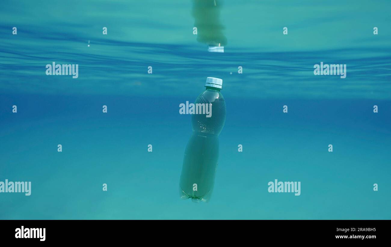 Green plastic bottle drifting under surface of blue water. Plastic ...
