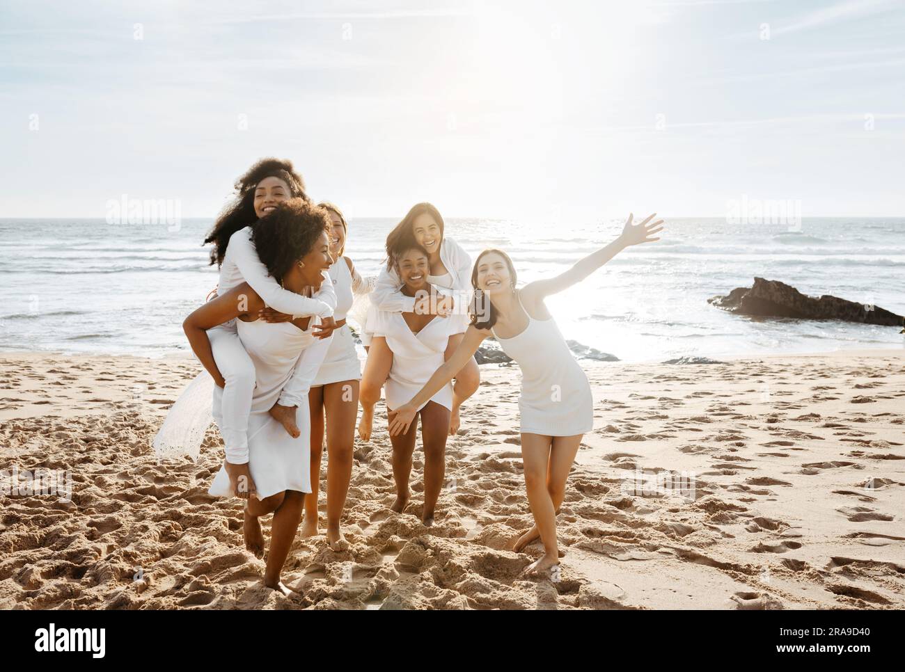 Female friends piggybacking each other at the beach, enjoying time ...