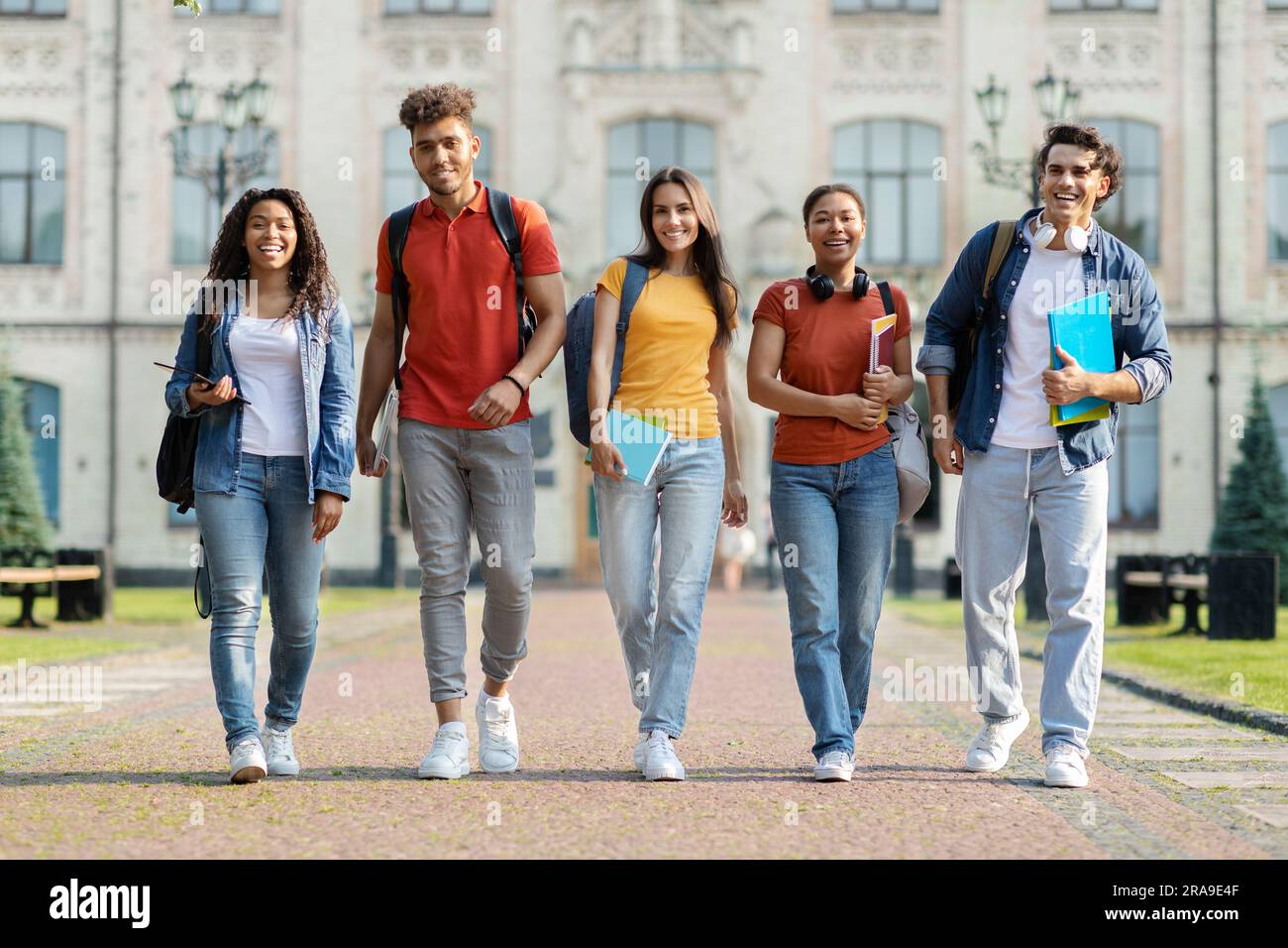 Happy university students walking together on campus, laughing and ...