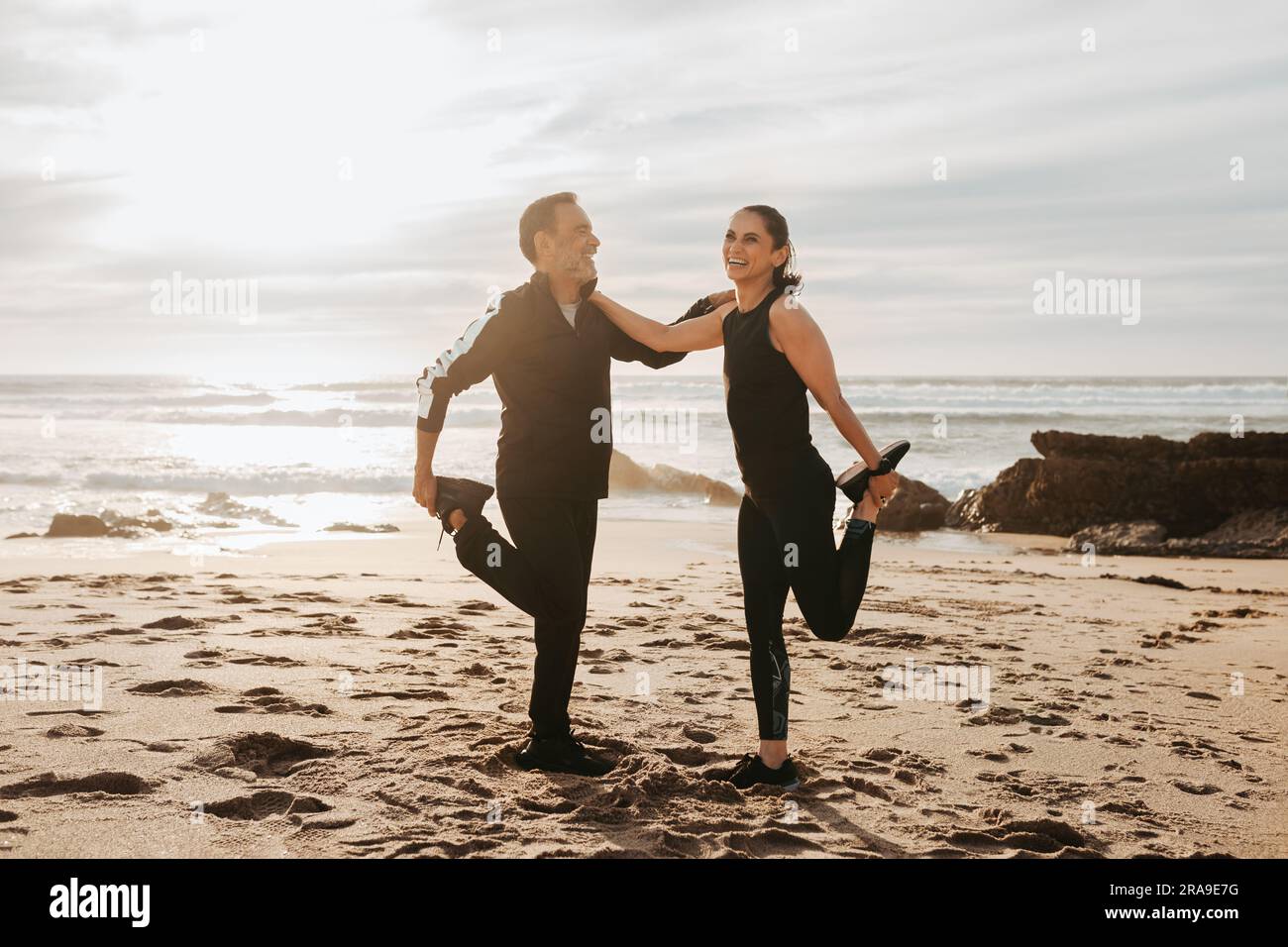 Laughing senior caucasian couple in sportswear doing legs stretching ...