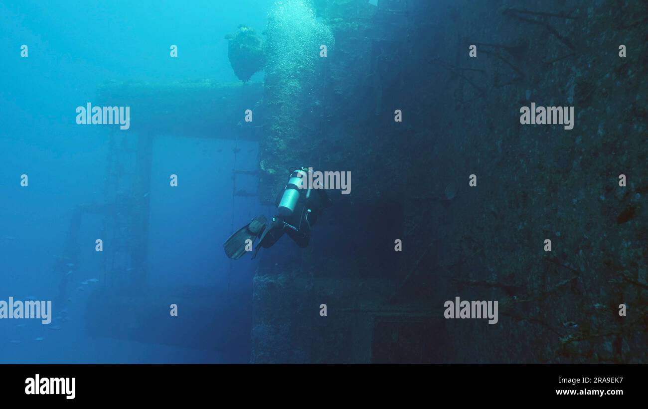 Scuba diver swim along deck of ferry Salem Express shipwreck, Back view ...