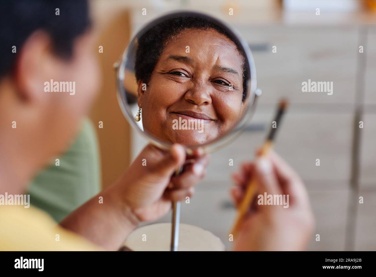 Focus on reflection of happy mature African American woman face in ...
