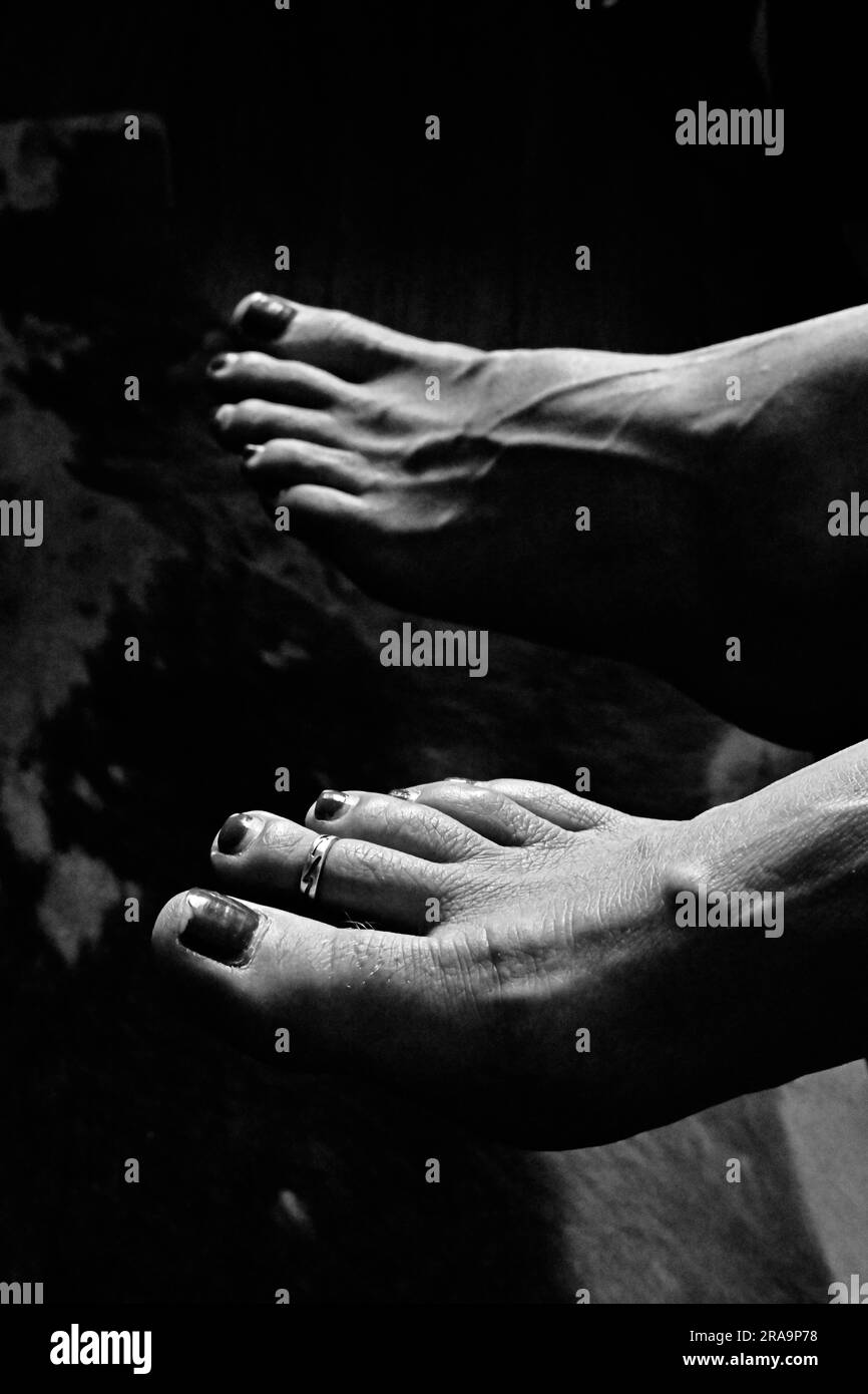 A woman's feet with crossed legs and painted toenails hang off the edge ...