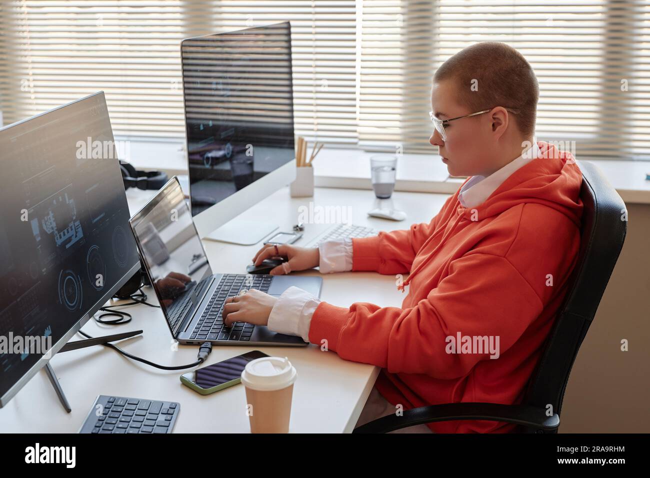 Young female IT manager or analyst typing on laptop keyboard while ...