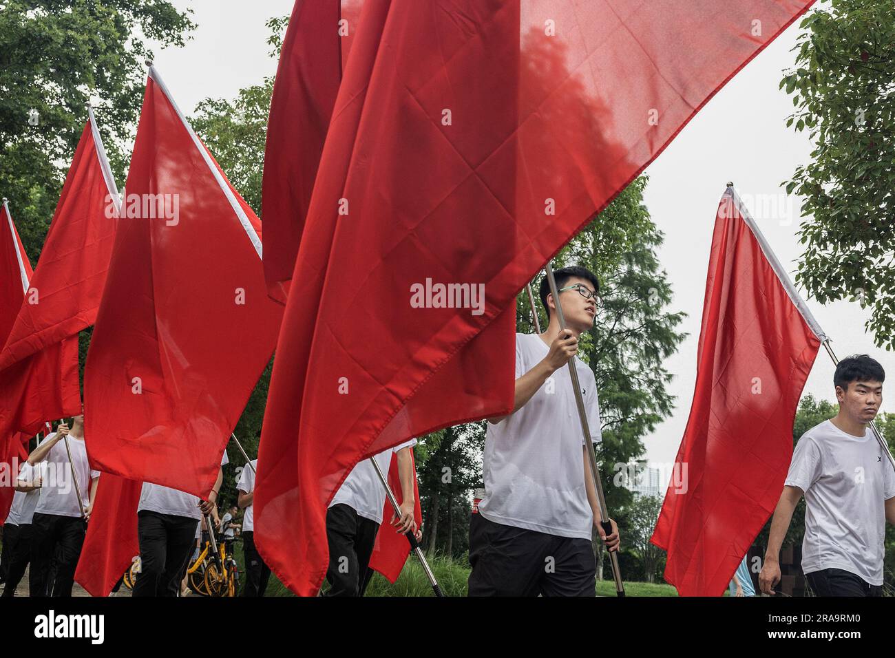 Wuhan, China. 01st July, 2023. Young men hold red flags during the ...