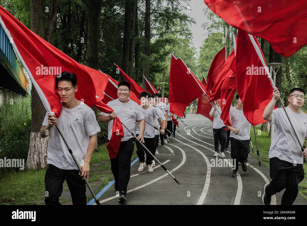 Wuhan, China. 01st July, 2023. Young men hold red flags during the ...