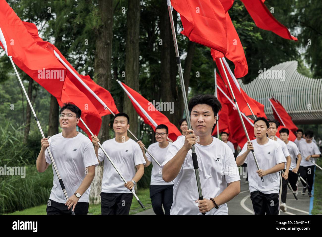 Wuhan, China. 01st July, 2023. Young men hold red flags during the ...