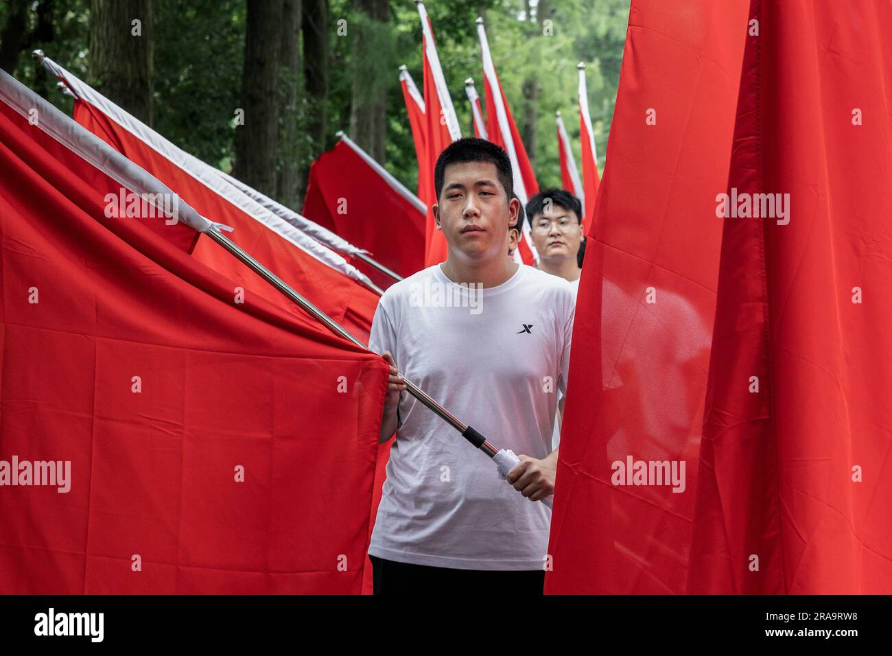 Wuhan, China. 01st July, 2023. Young men hold red flags during the ...