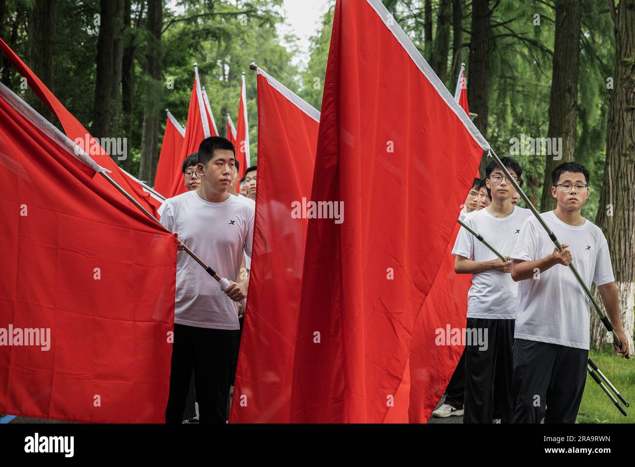 Wuhan, China. 01st July, 2023. Young men hold red flags during the ...