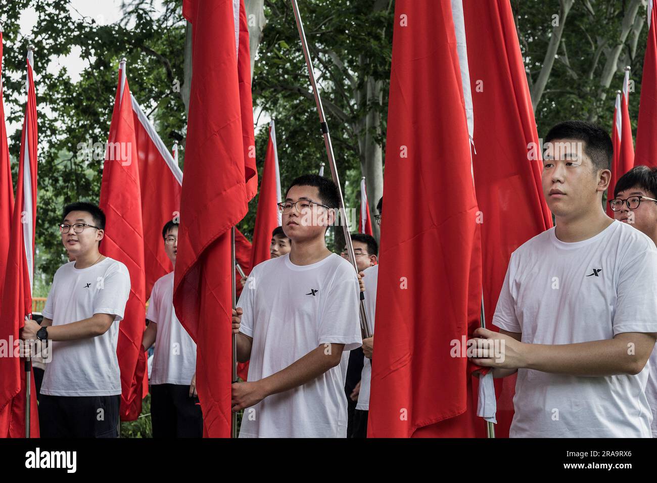 Wuhan, China. 01st July, 2023. Young men hold red flags during the ...