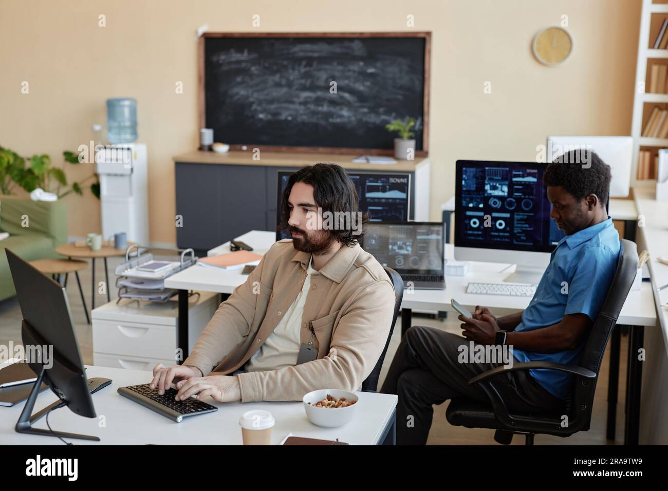 Young serious cyber security manager typing on computer keyboard while ...