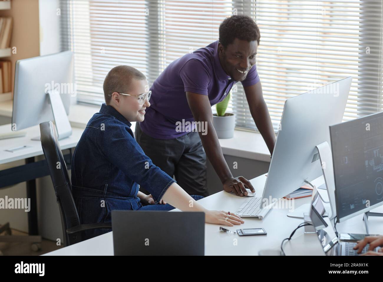 Two happy young intercultural cyber security managers looking at screen ...