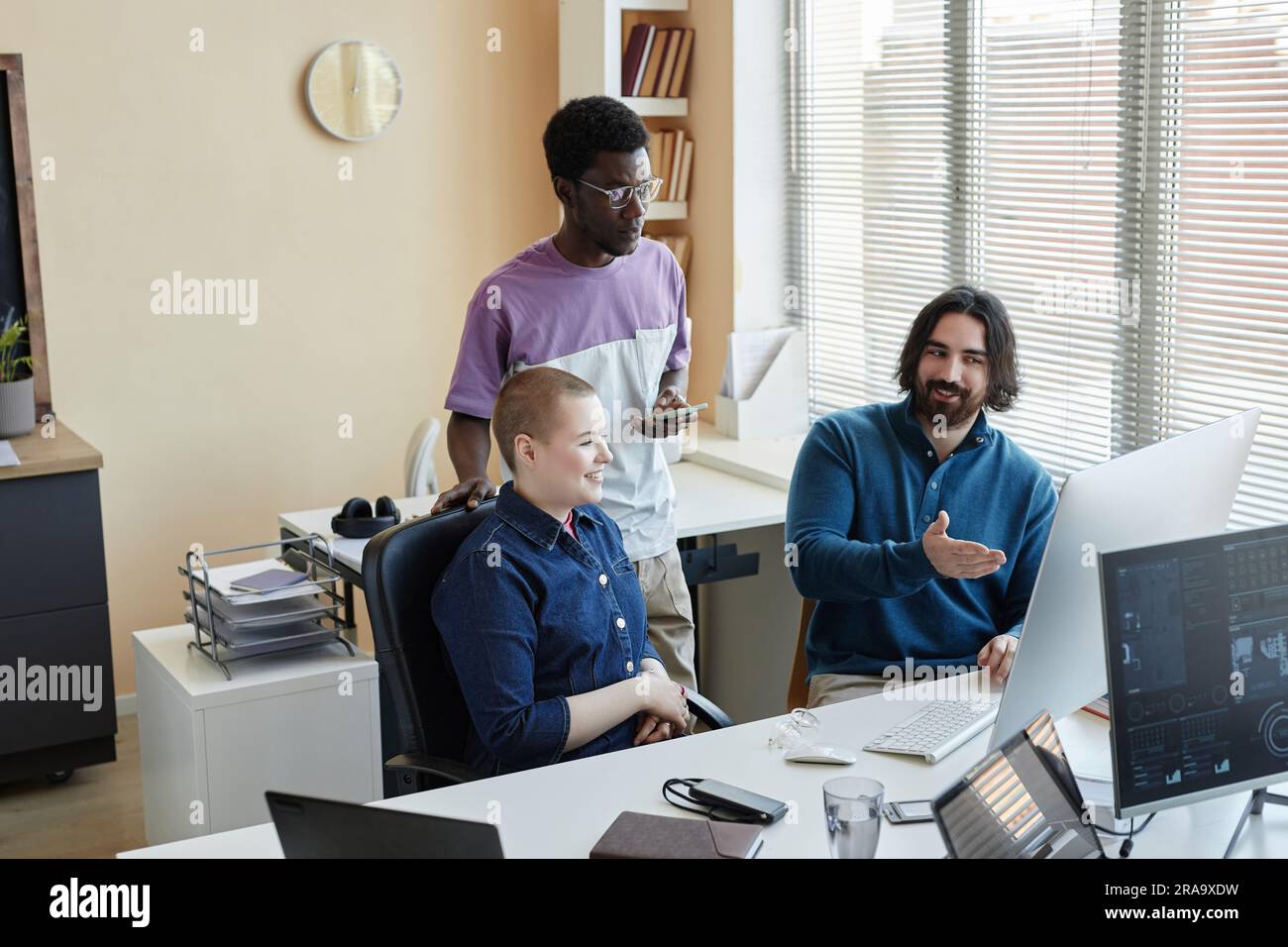 Confident smiling businessman pointing at computer screen during discussion of online data with ...