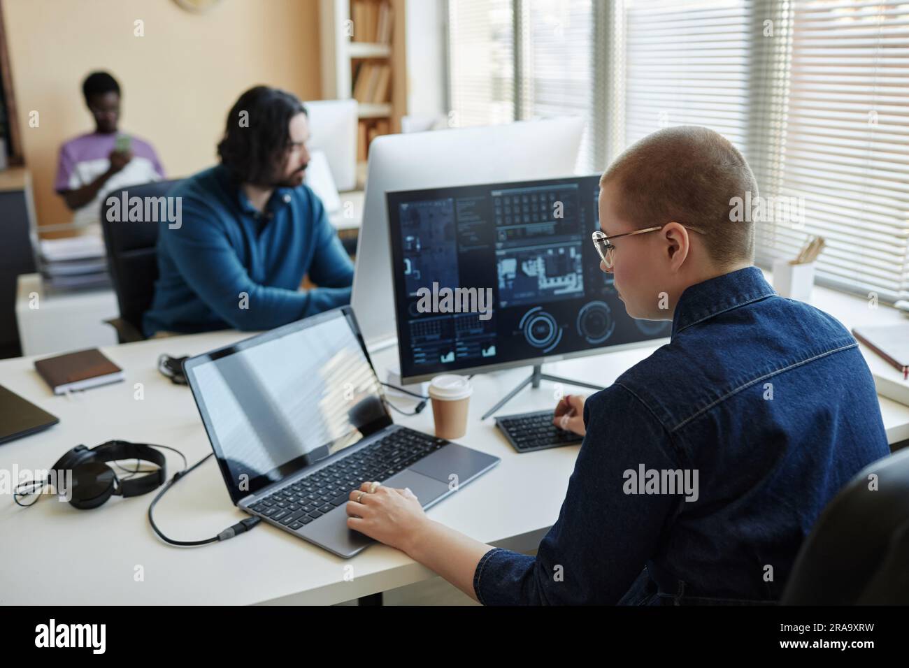 Young female cyber security manager using laptop while sitting by ...