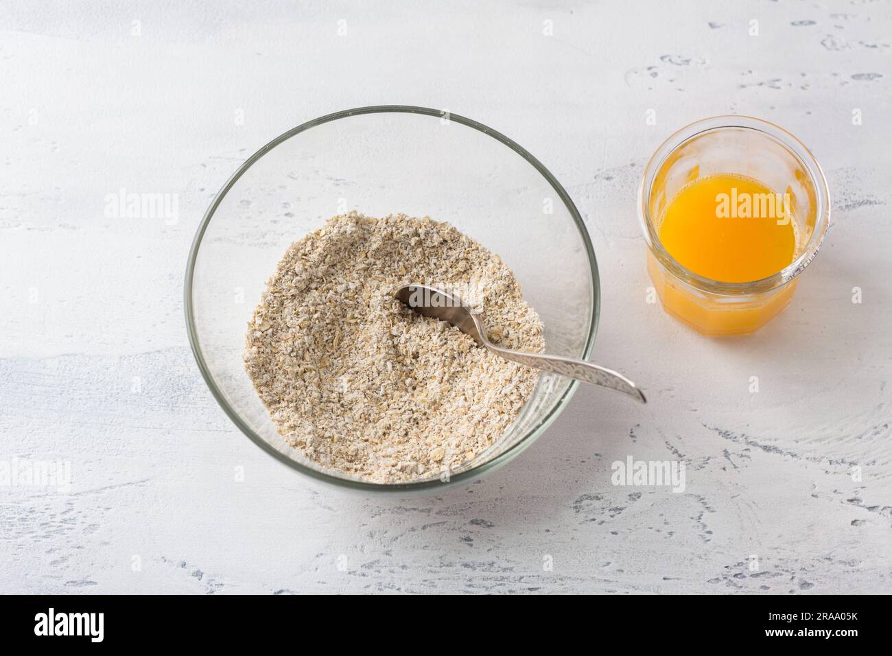 A glass bowl with ground oatmeal and a glass of freshly squeezed orange ...