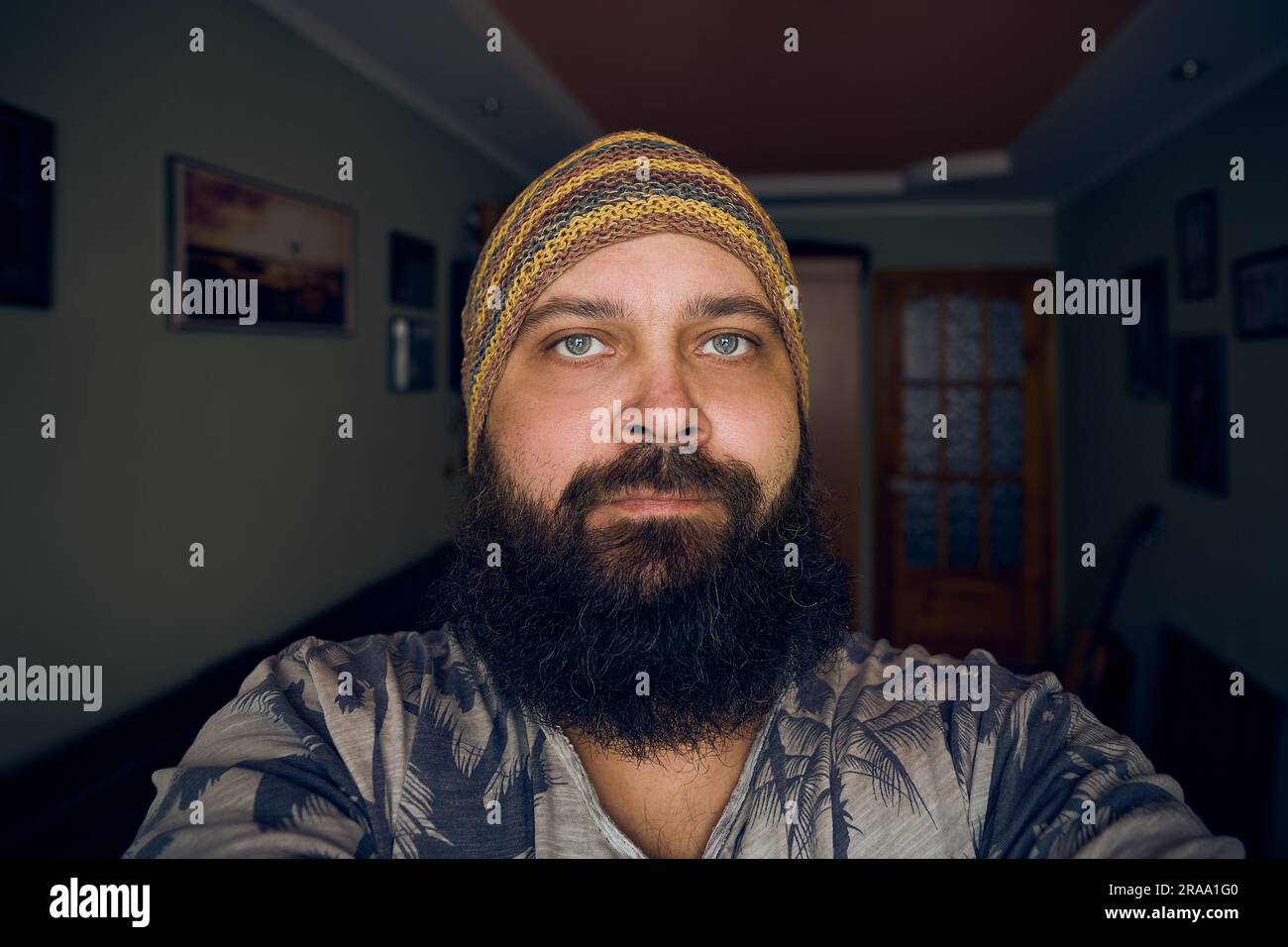 A man with a beard wearing a striped hat and shirt, looking up into the ...