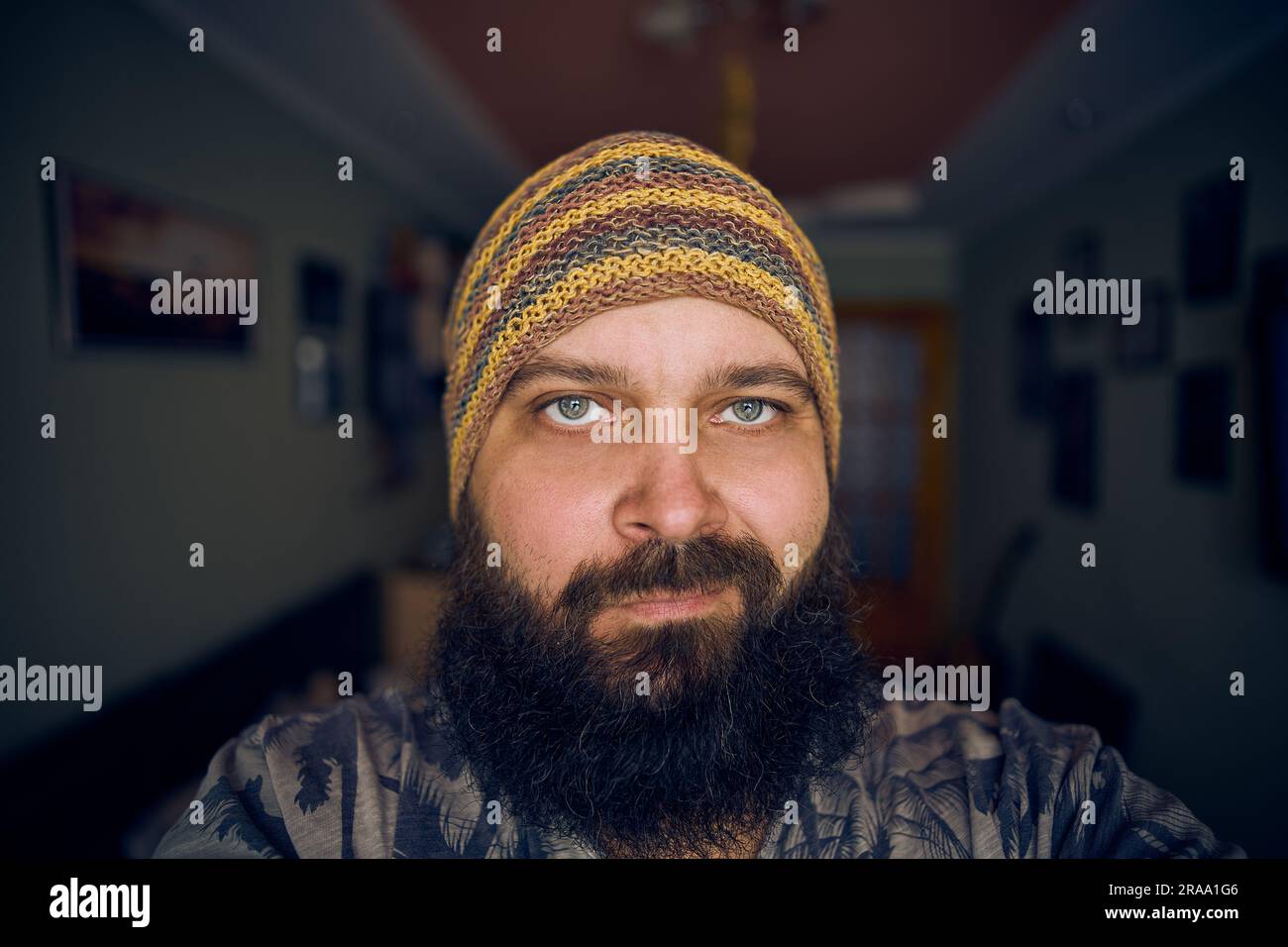 A man with a beard wearing a striped hat and shirt, looking up into the ...