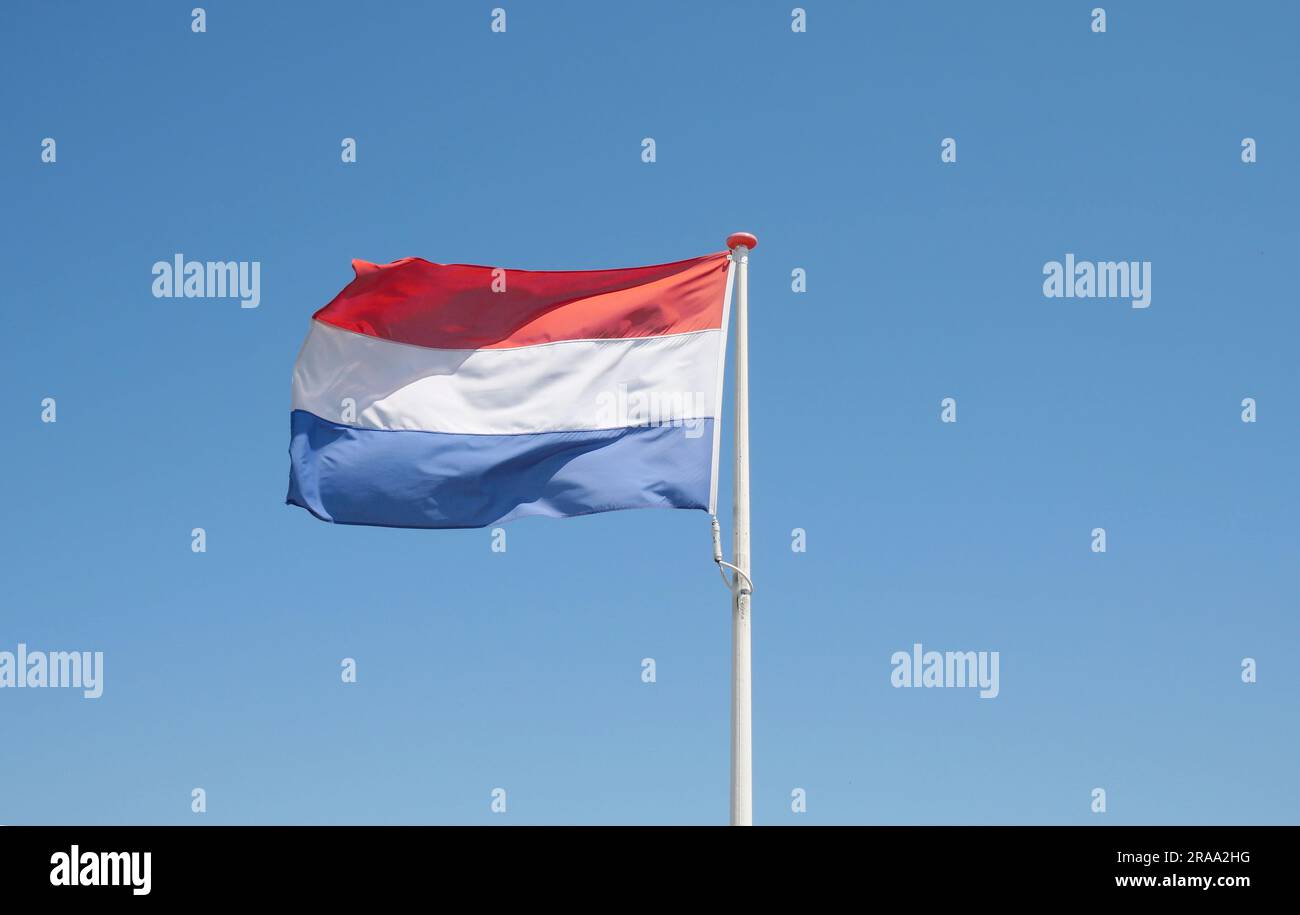 Flag of the Netherlands waving in the wind against a clear blue sky ...