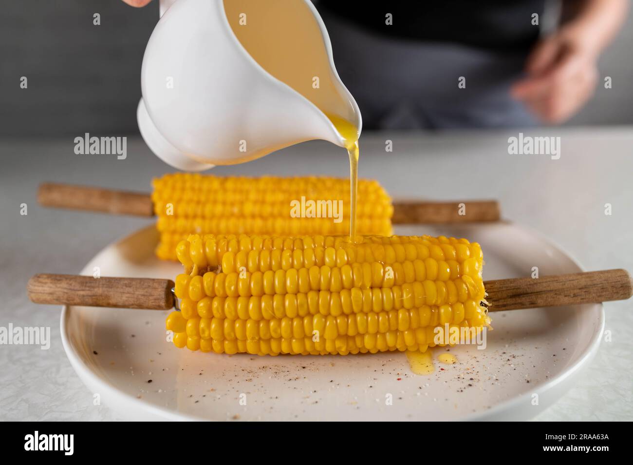 Pouring melted butter over corn on the cob Stock Photo - Alamy