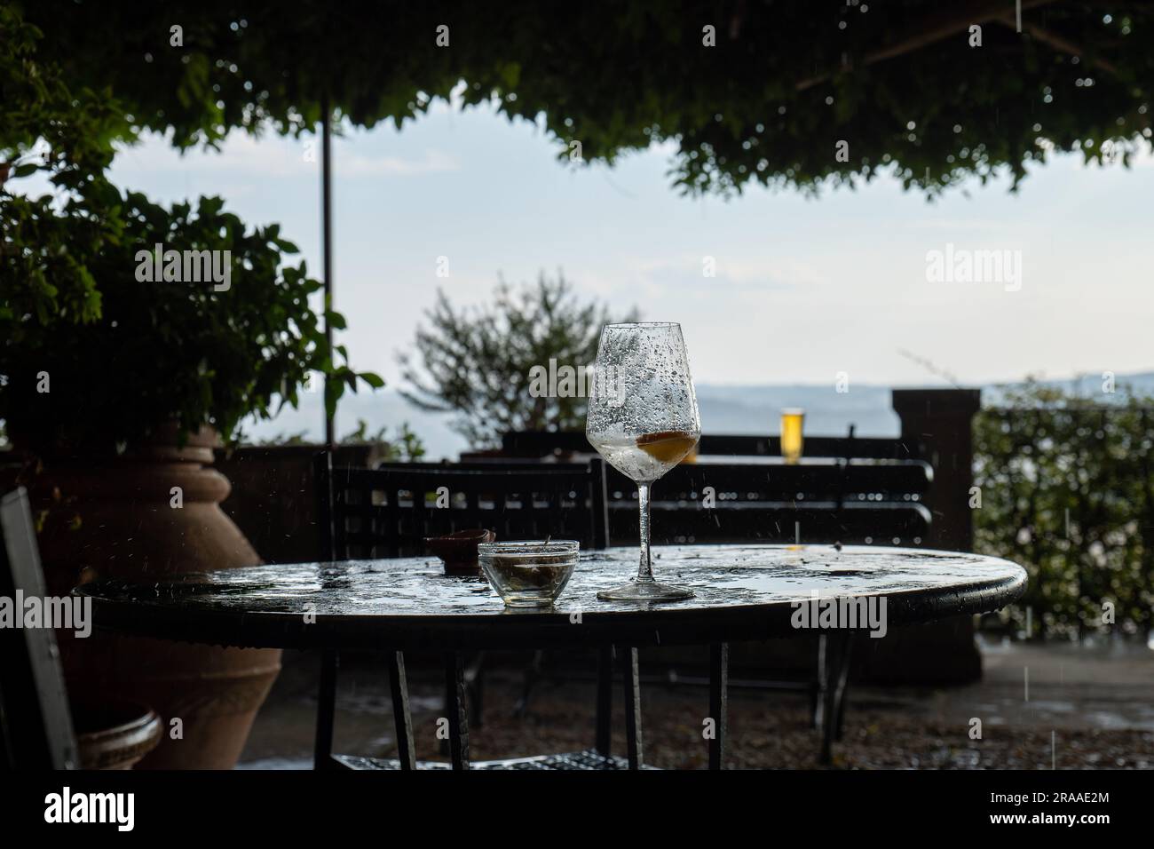single glas of wine on a table in the rain moody Stock Photo - Alamy