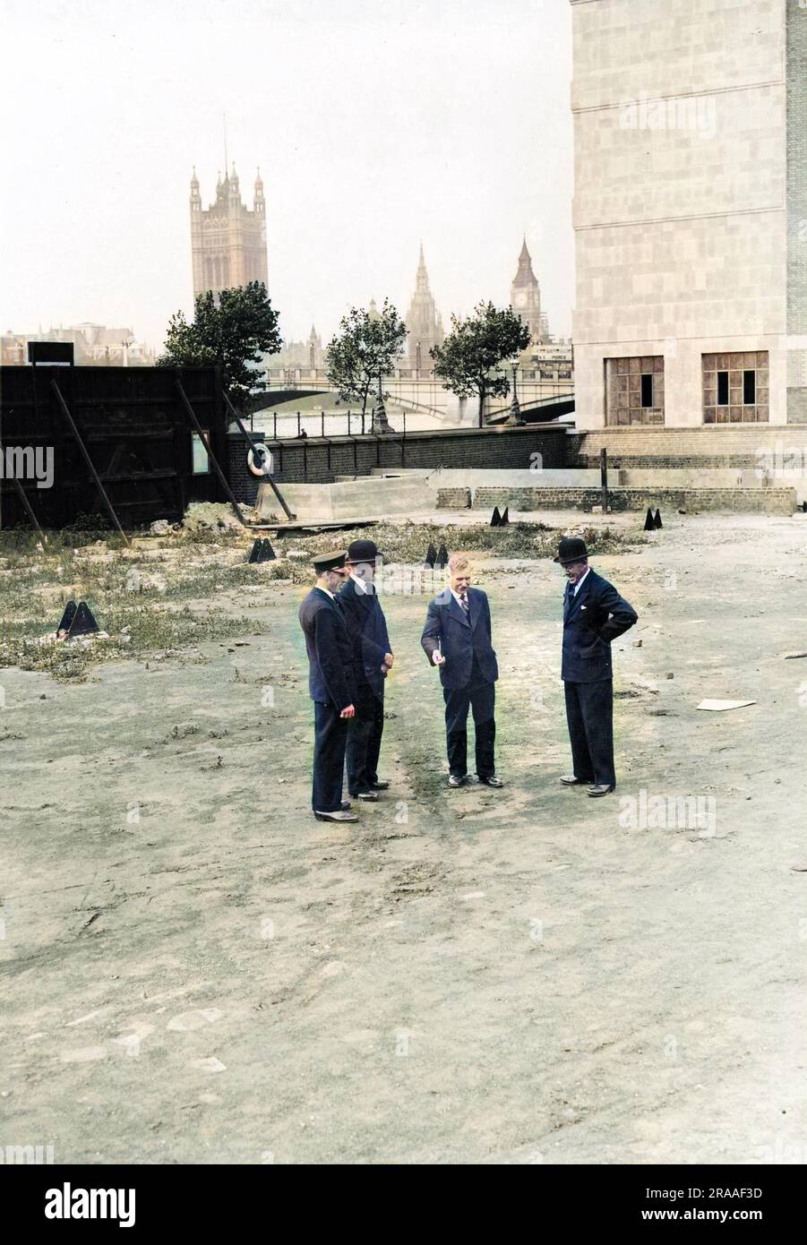 A group of men talking on a piece of open ground, with the Houses of ...