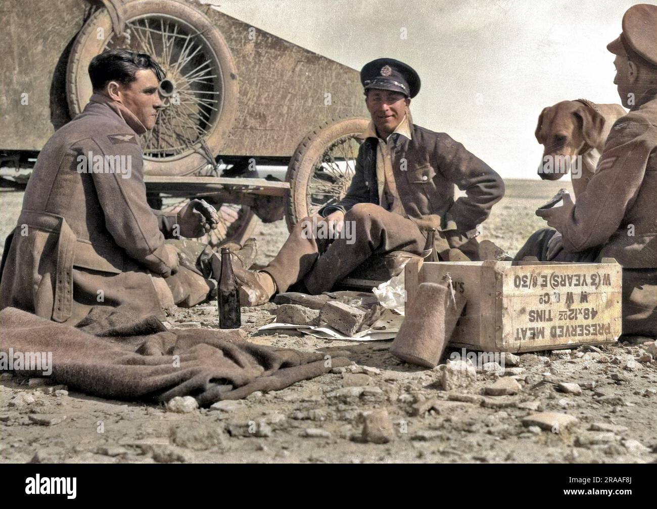 Three men in uniform having a picnic in a barren landscape, watched by ...