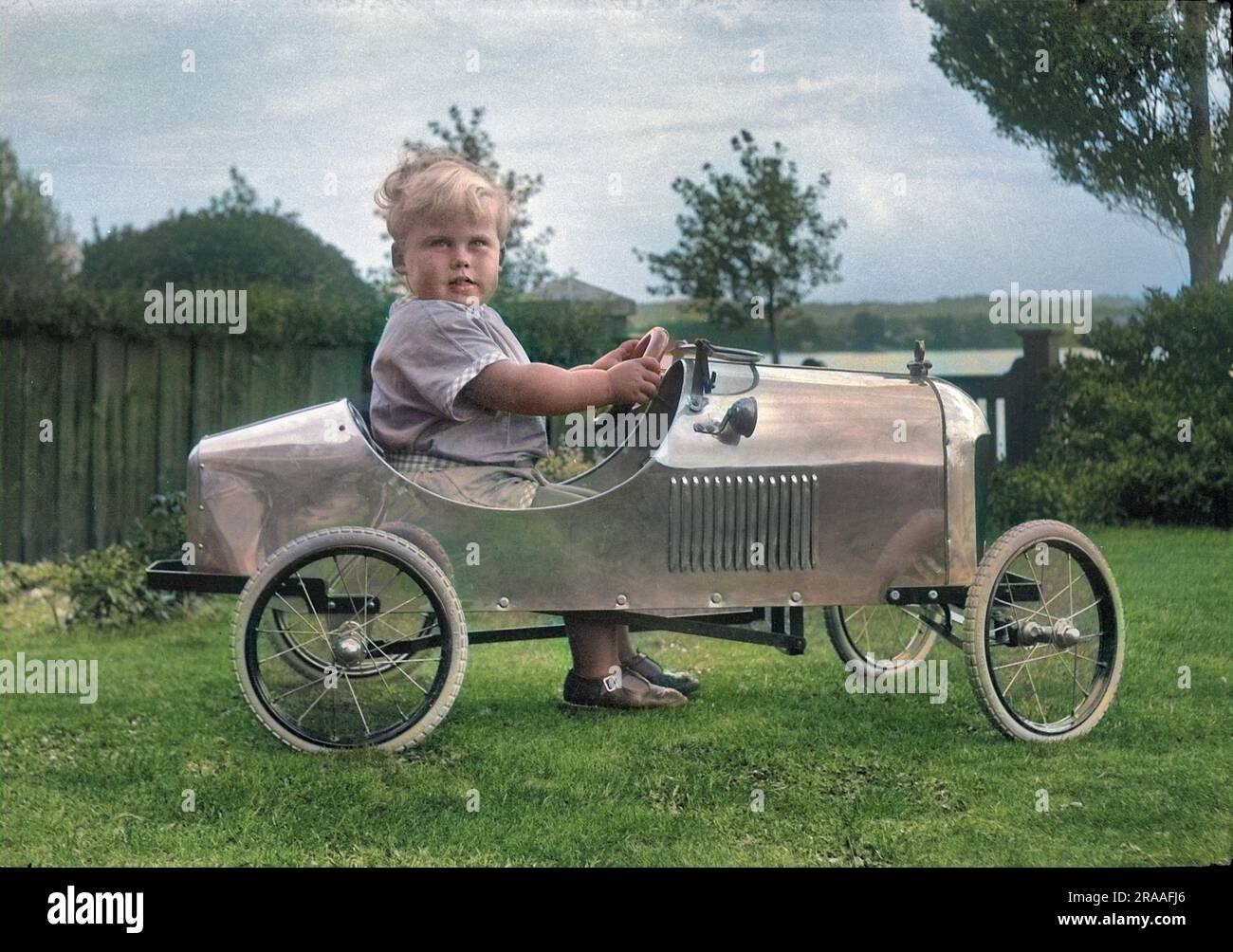 A little boy riding in a toy car, with his feet resting firmly on the ...