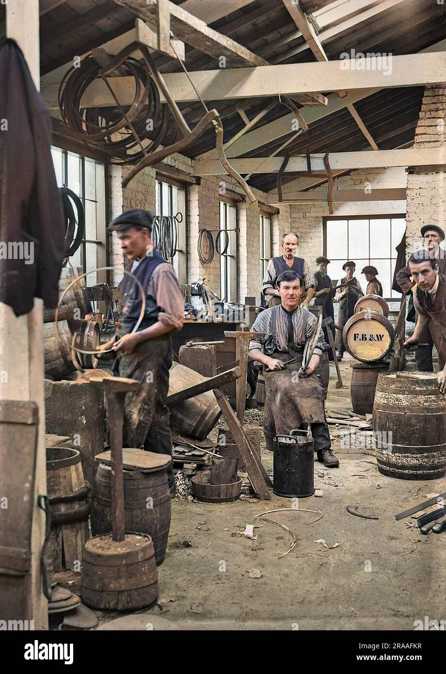 Men and boys in a workshop, most of them looking towards the camera ...