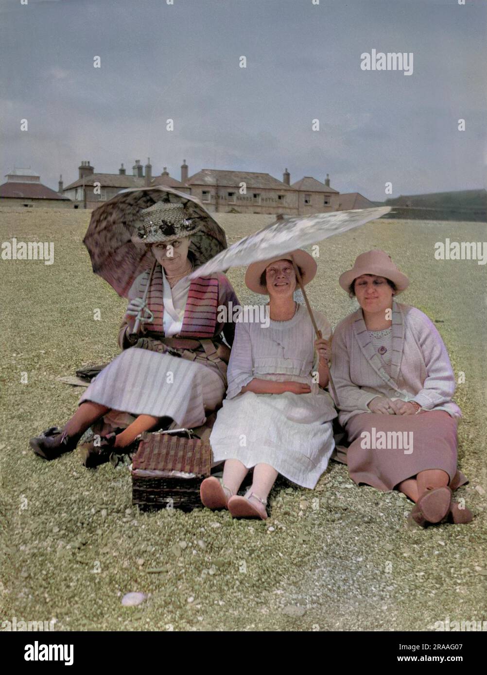 Three women sitting on the ground, shading themselves from the sun with ...