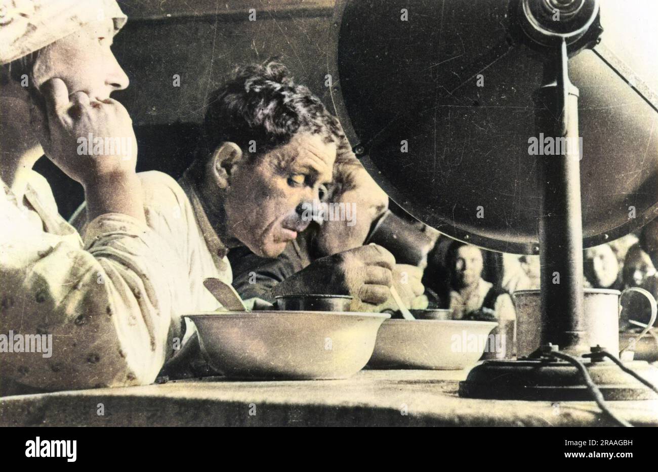 Withered looking Men and women eat lunch in a 1920's Russian commune ...