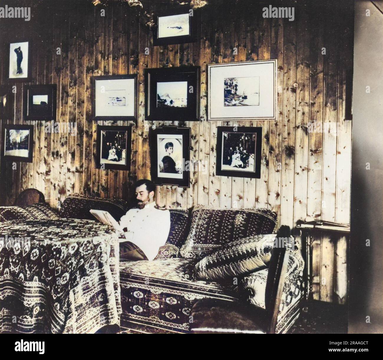 Tsar Nicholas II (1868 - 1918) seated and reading in his hunting Lodge in Sarikamis, a town in ...