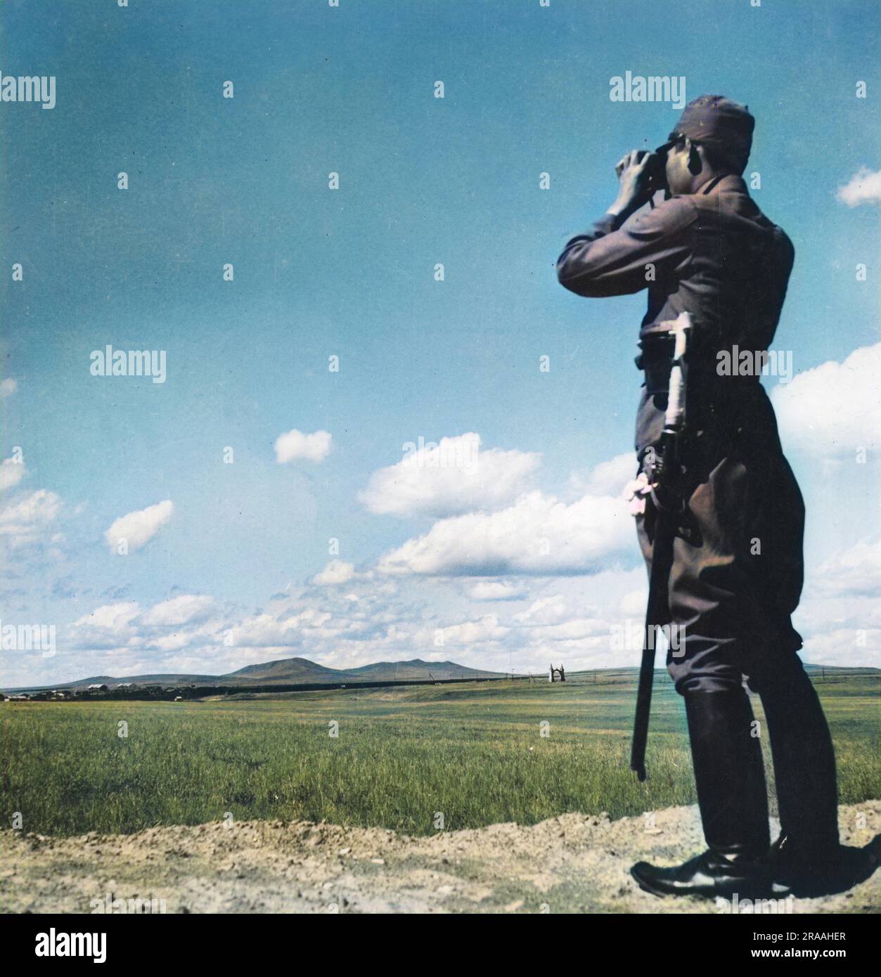 A Japanese border guard on look-out duty uses binoculars to watch a ...