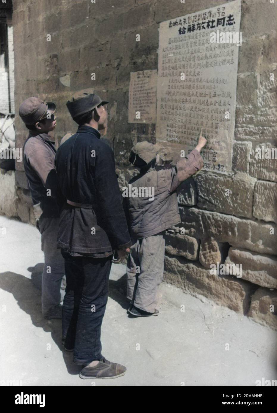 Chinese people study a wall poster during the Sino-Japanese War Date ...