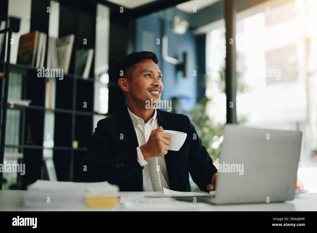 Portrait of an Asian male business owner standing with a computer ...