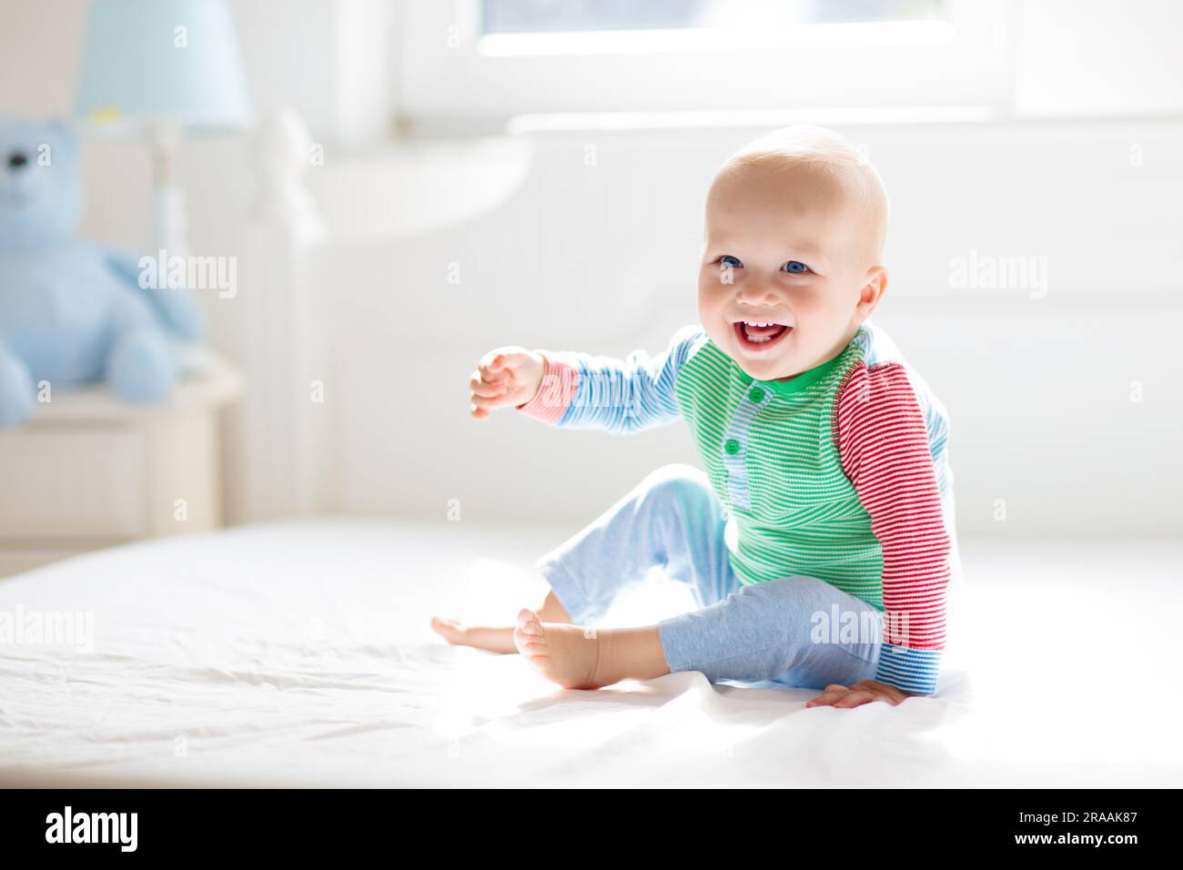 Baby boy crawling on bed. Little child playing in white sunny bedroom ...