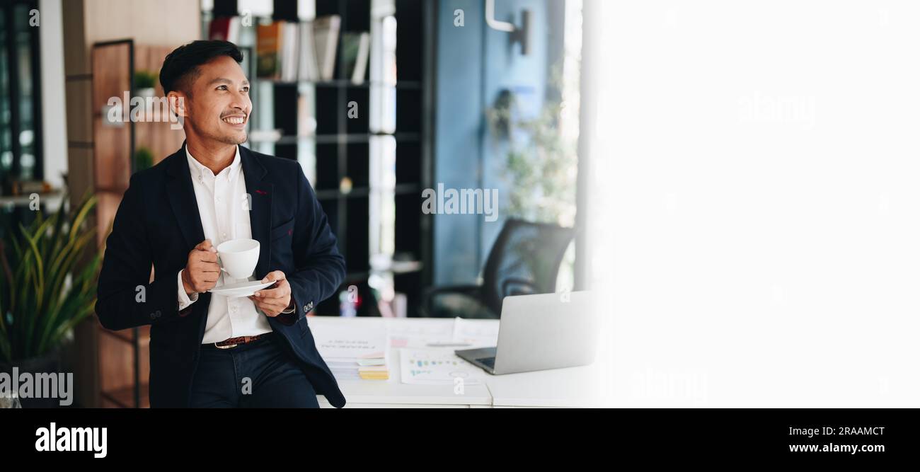 Portrait of an Asian male business owner standing with a computer ...