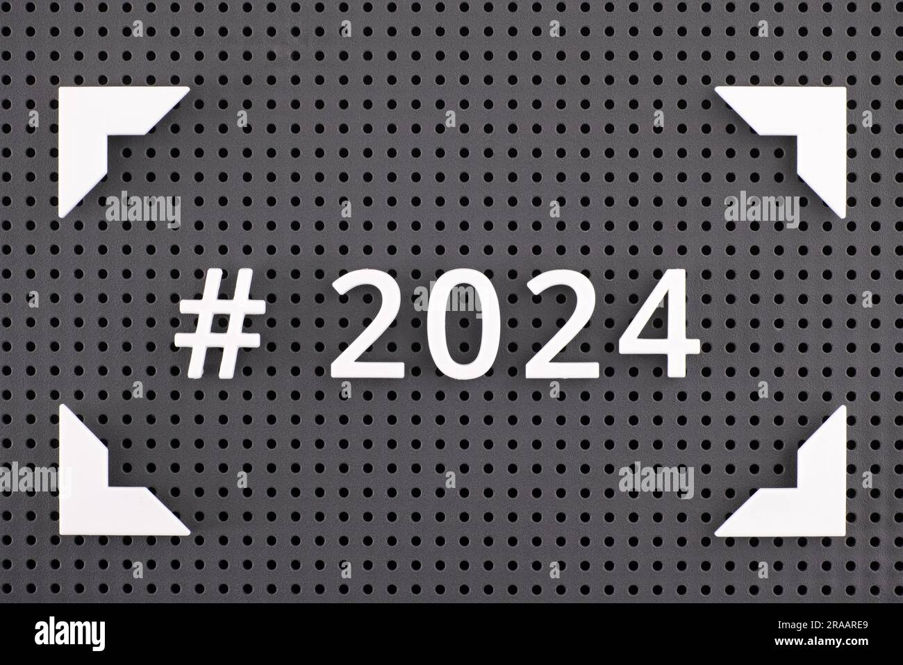 Hashtag 2024 written with white numbers in a frame on a gray pegboard ...