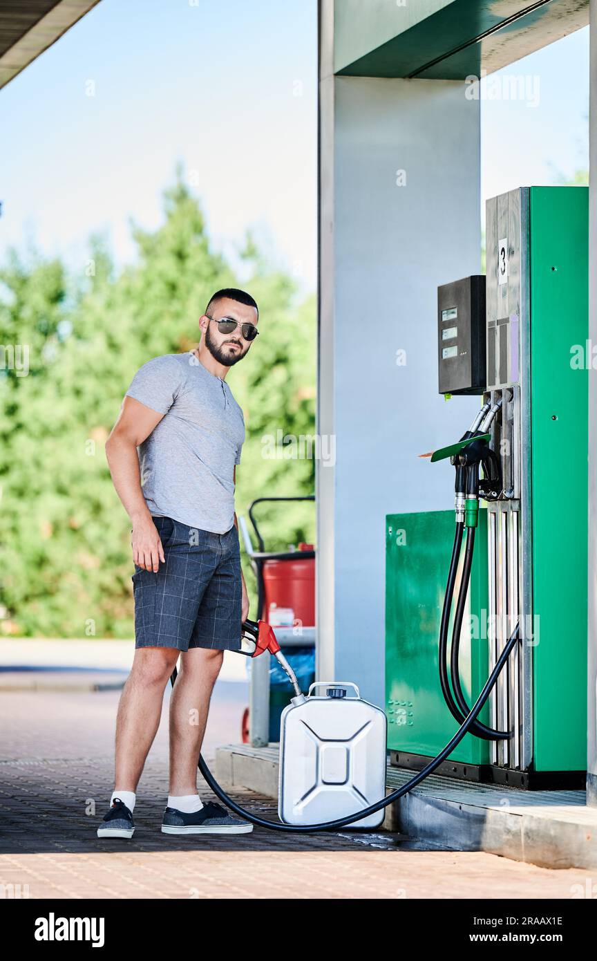 Portrait of young driver filling canister with gasoline. Man refueling ...
