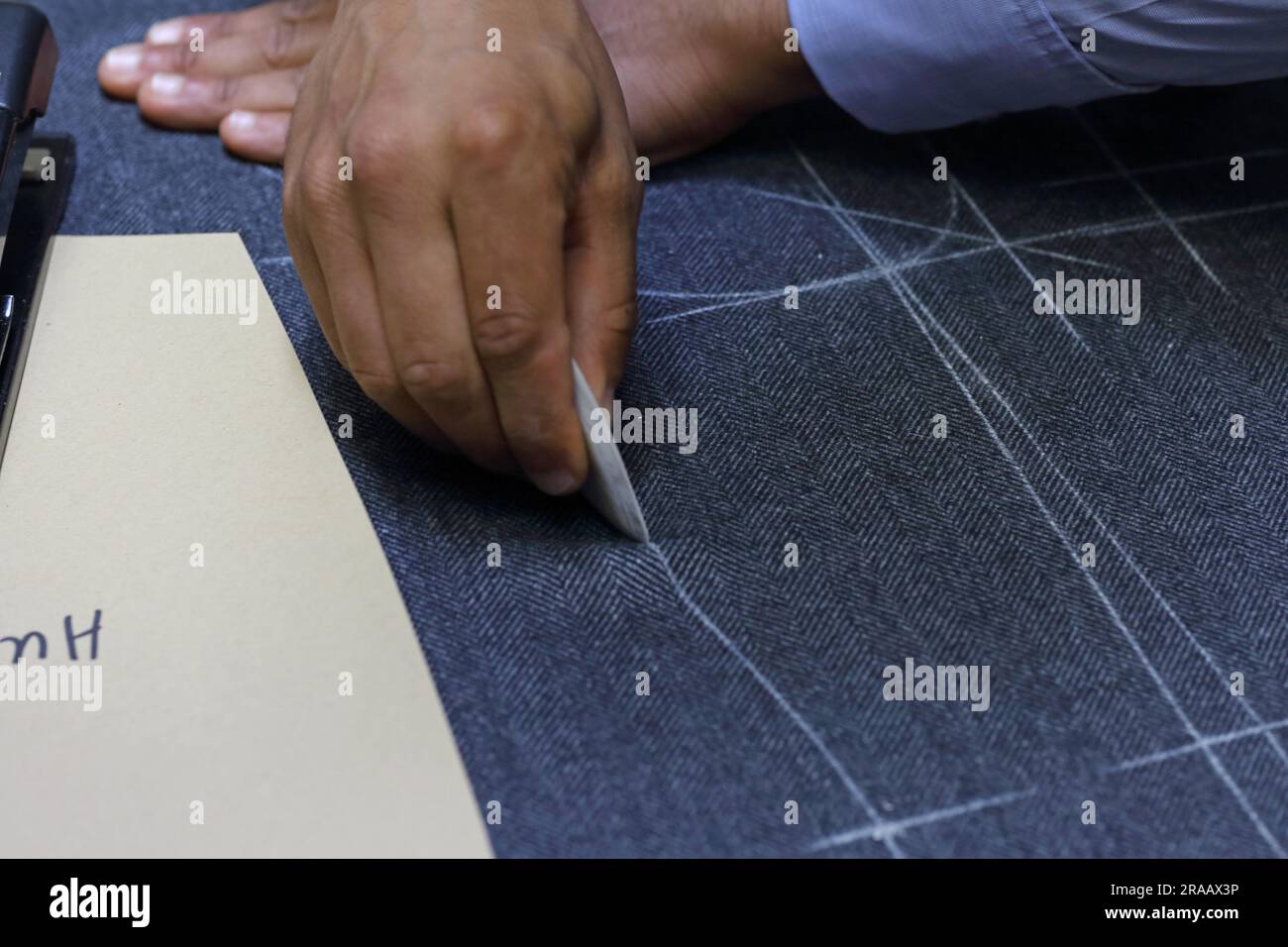 Tailor marking cloth pattern with chalk at Anderson & Sheppard bespoke ...