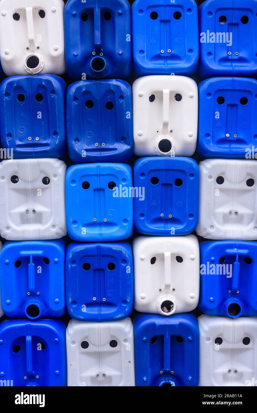 Artwork of surprised faces made from blue and white plastic barrels ...