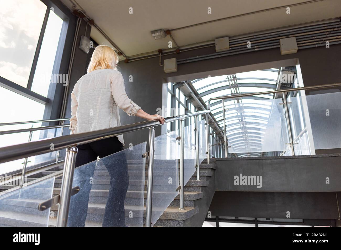 woman climbing the stairs holding on to the railing Stock Photo - Alamy