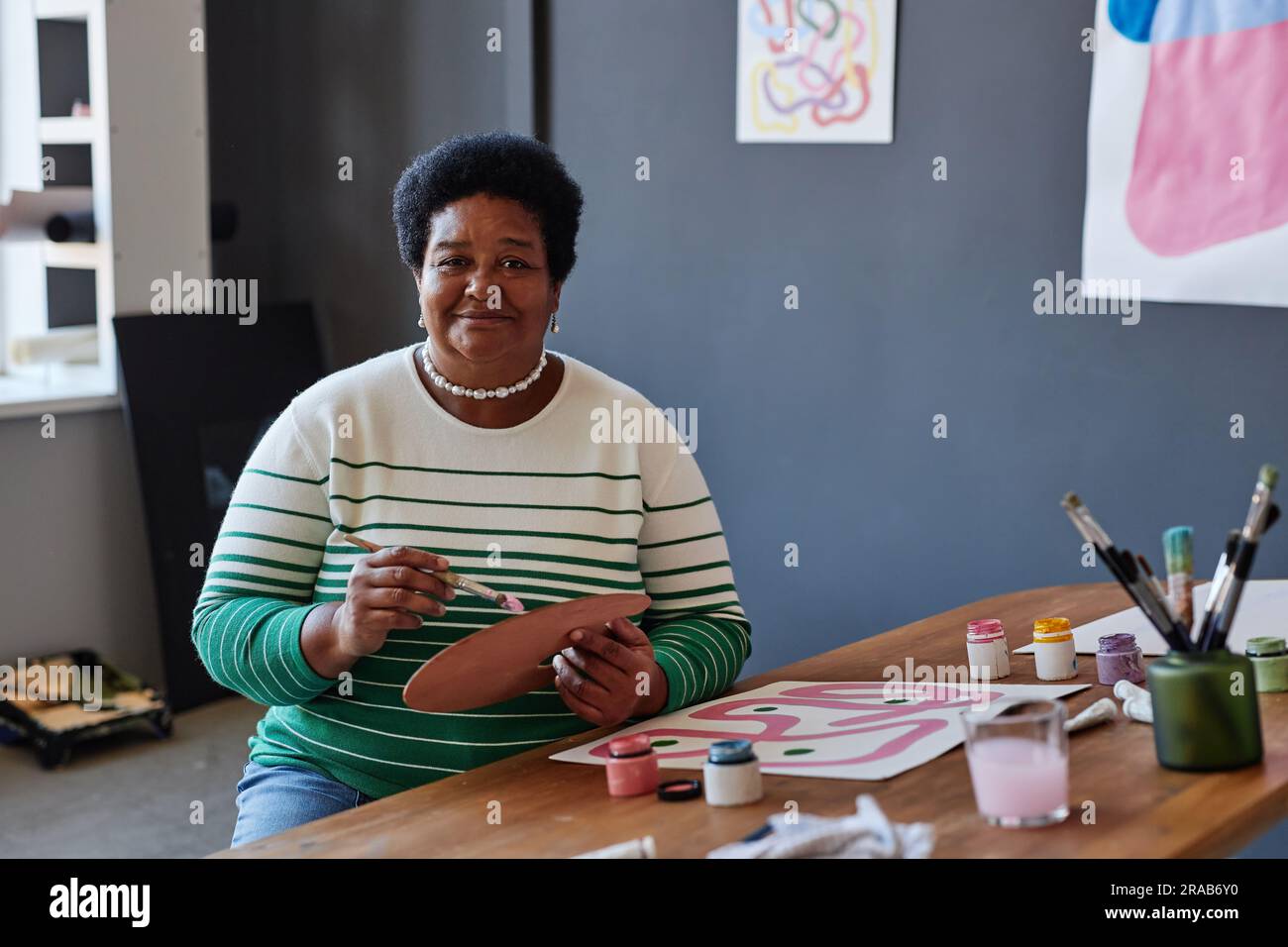 Confident professional painter with watercolor palette looking at ...