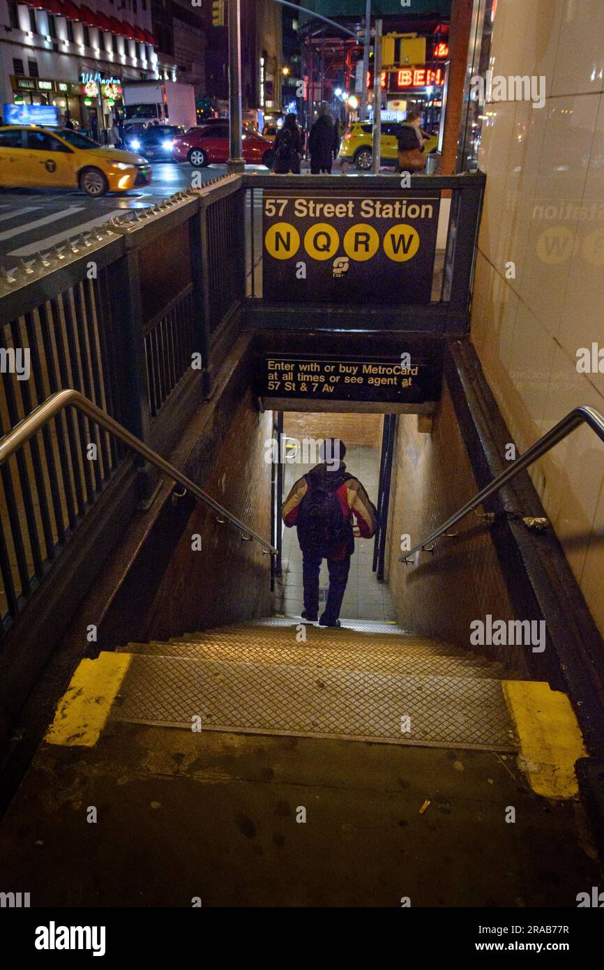 A man walks down the stairs to the 57th Street subway station at night ...