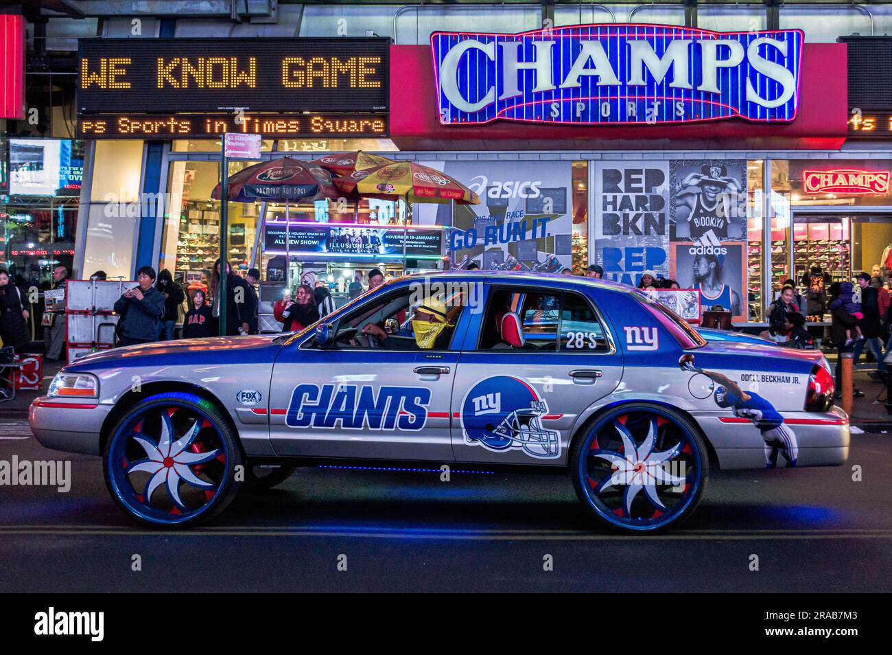 A car with large wheel rims drives down 42nd Street at Times Square in ...